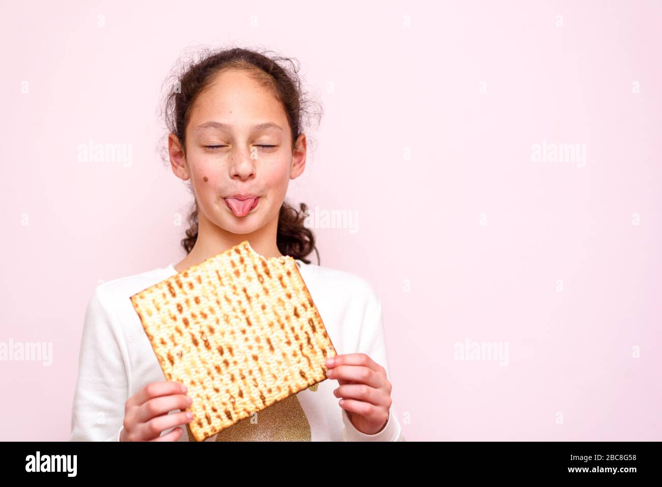 Portrait of the cute teenager girl holding matzah and shows tongue ...