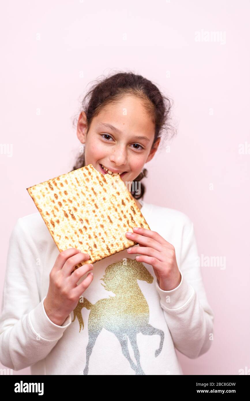 Portrait of the cute teenager girl holding matzah. Jewish child eating ...