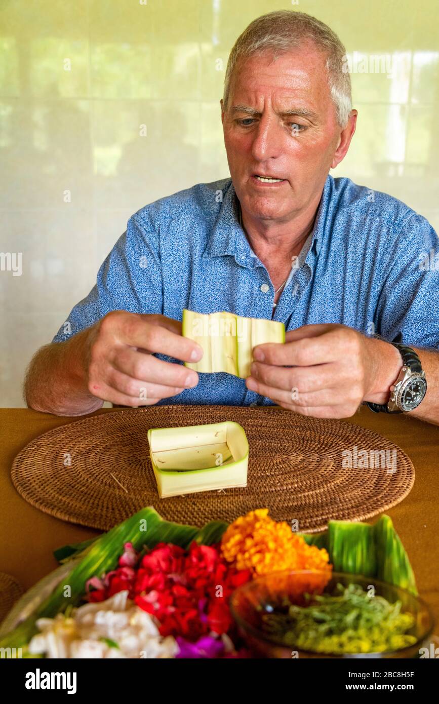 Vertical portrait of a tourist making Canang Sari used in blessings in ...