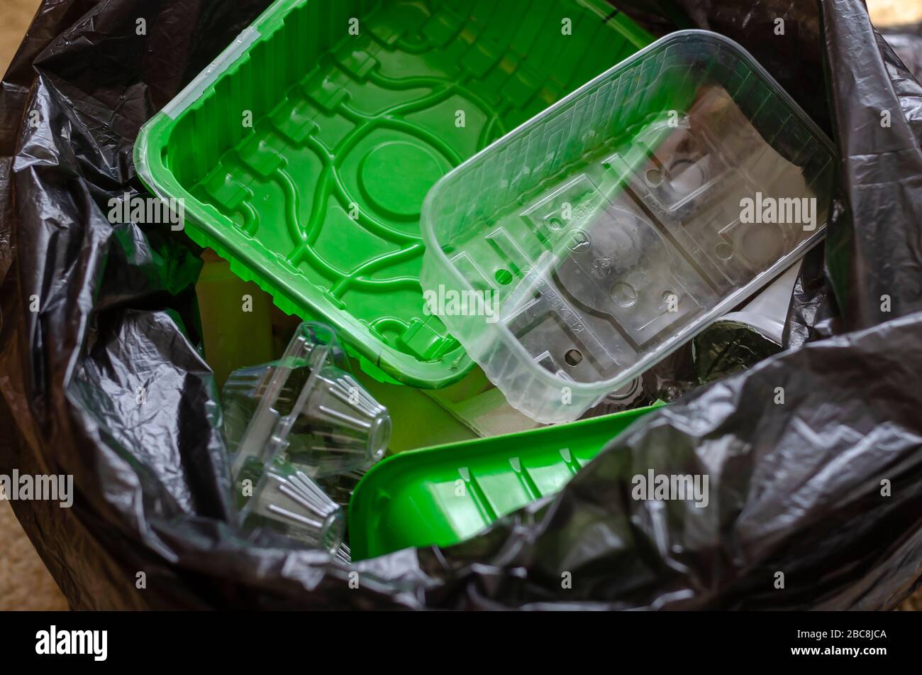Plastic containers in a trash bag. Black trash bag close up. Food ...