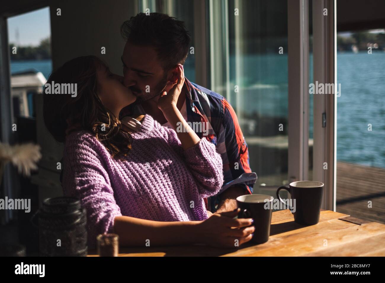 Couple kissing and drinking coffee in a house by the river. Beautiful ...