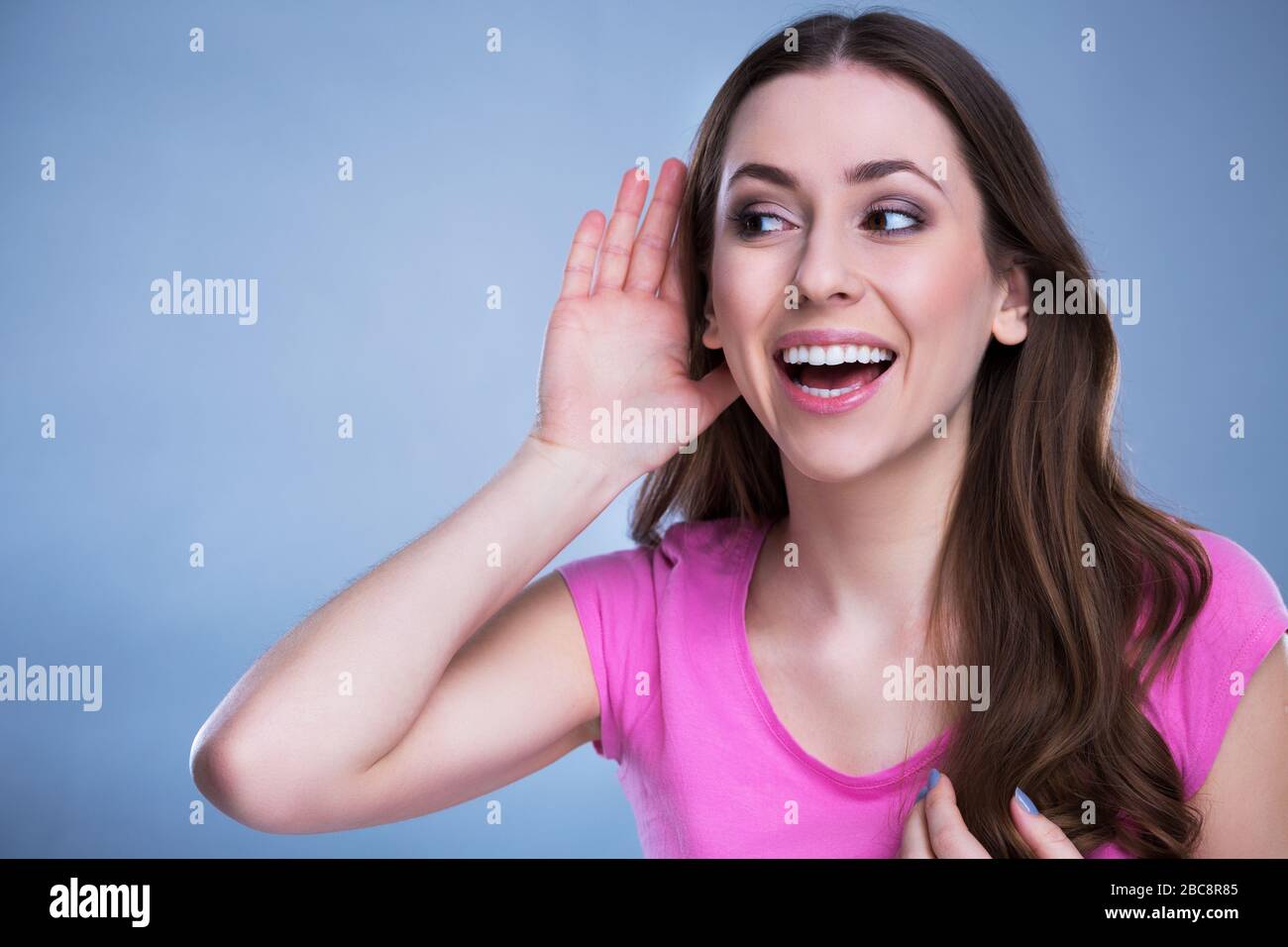 Woman with hand to ear listening Stock Photo - Alamy