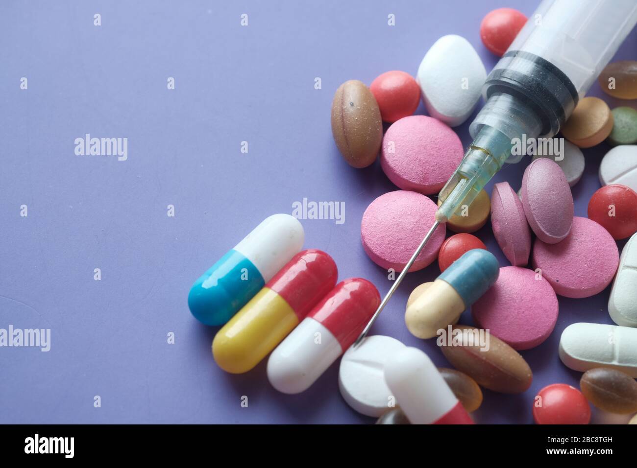 Assorted medical drugs and syringe on color background Stock Photo - Alamy