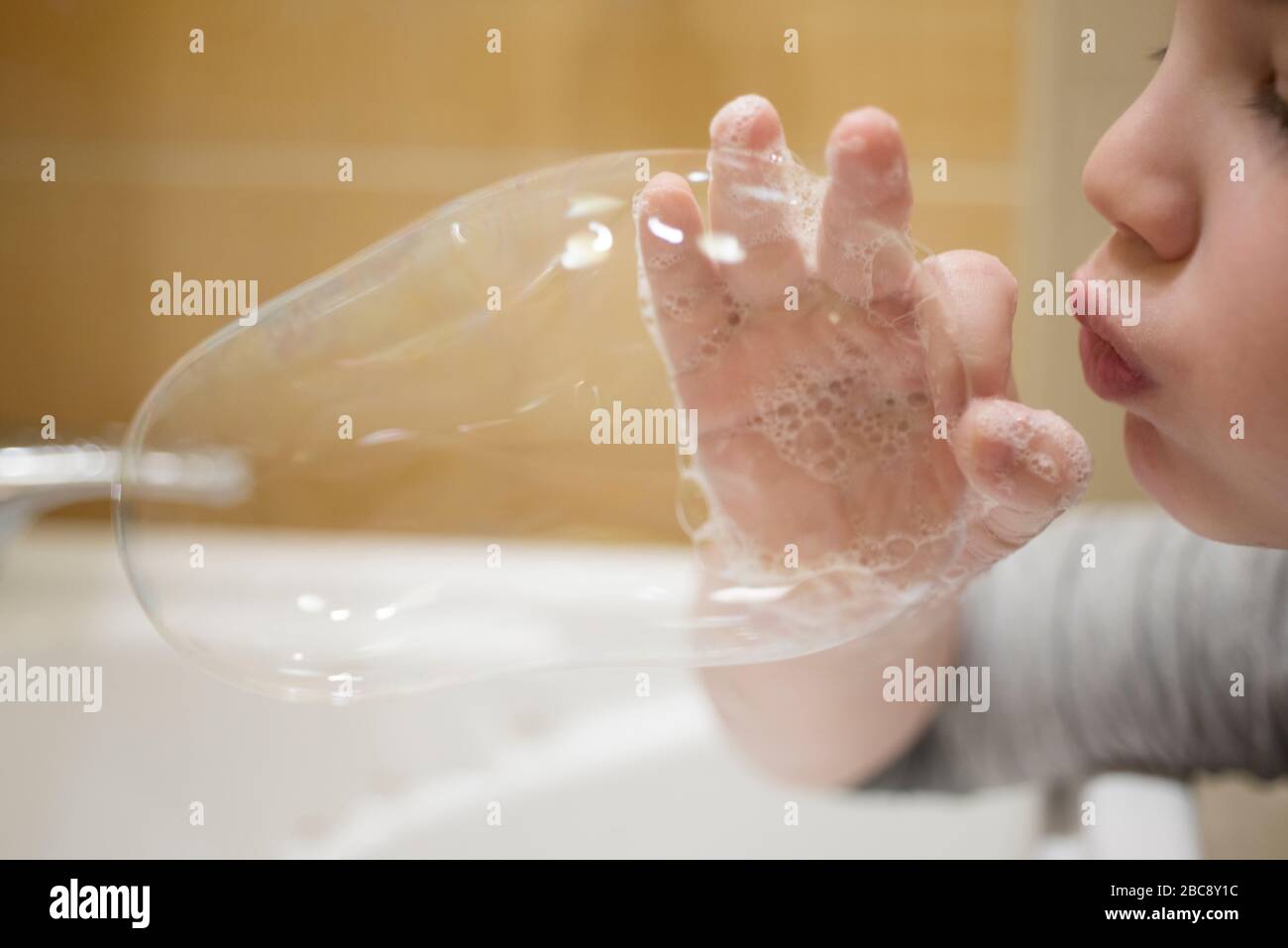 Young Boy Blowing a Soap Balloon Stock Photo - Alamy
