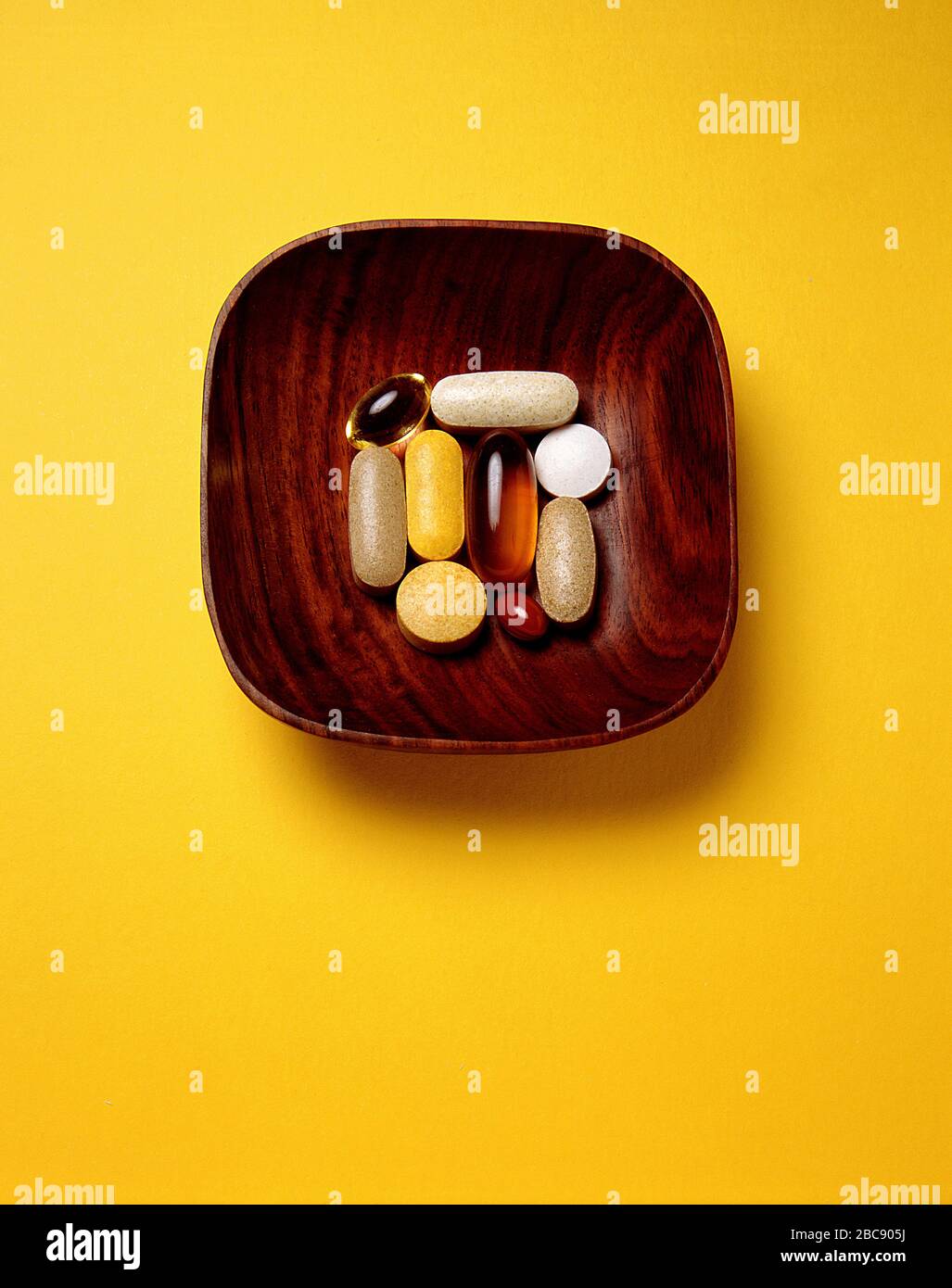 various vitamin gel capsules and pills in a small wooden bowl Stock ...