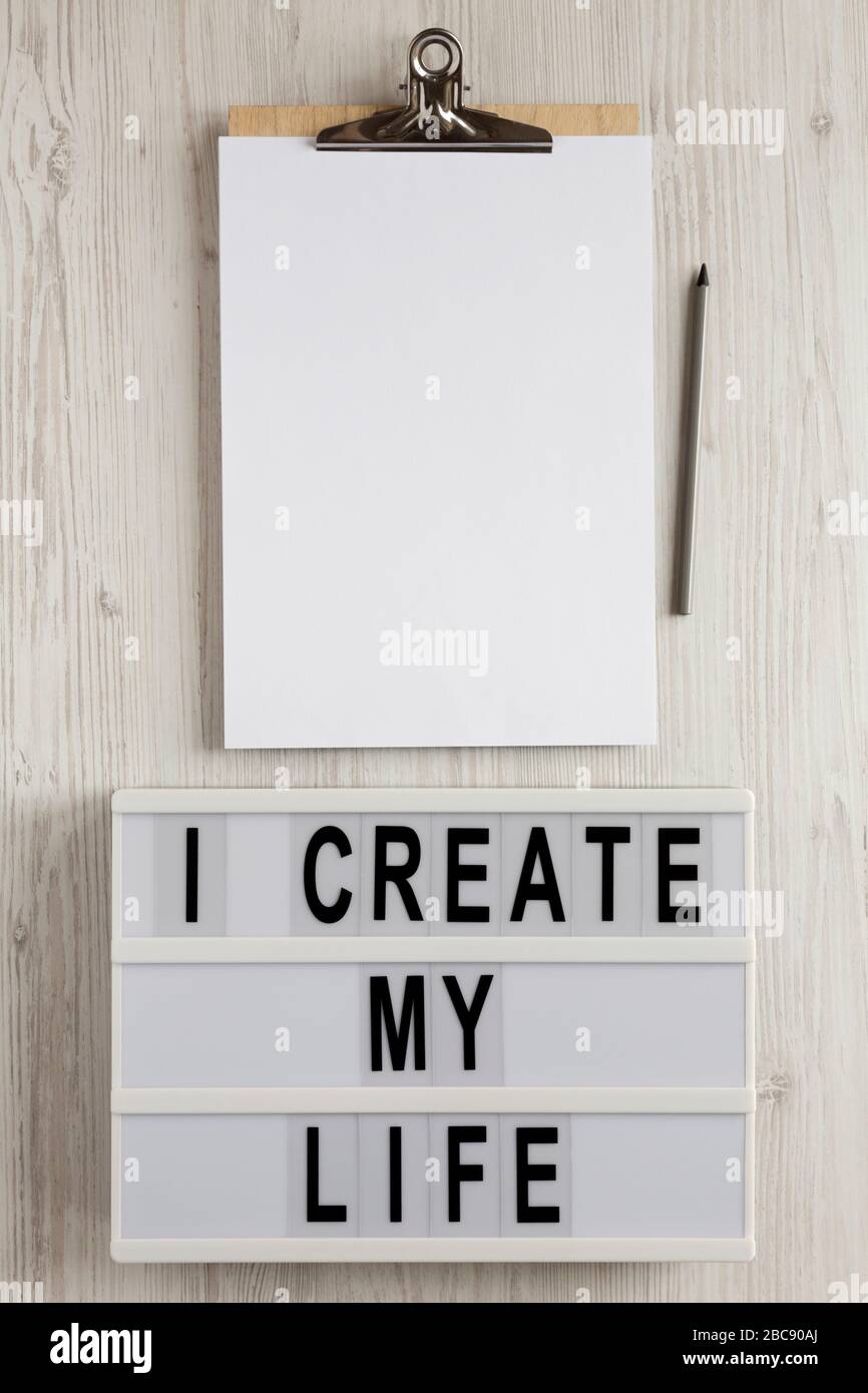 'I create my life' words on a lightbox, clipboard with blank sheet of ...