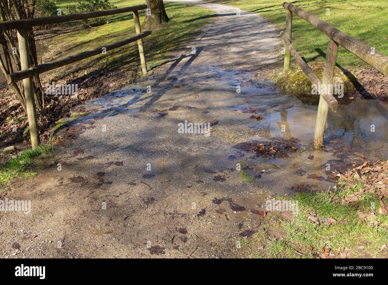 Small stone bridge for a footpath over a small creek flooded with water ...