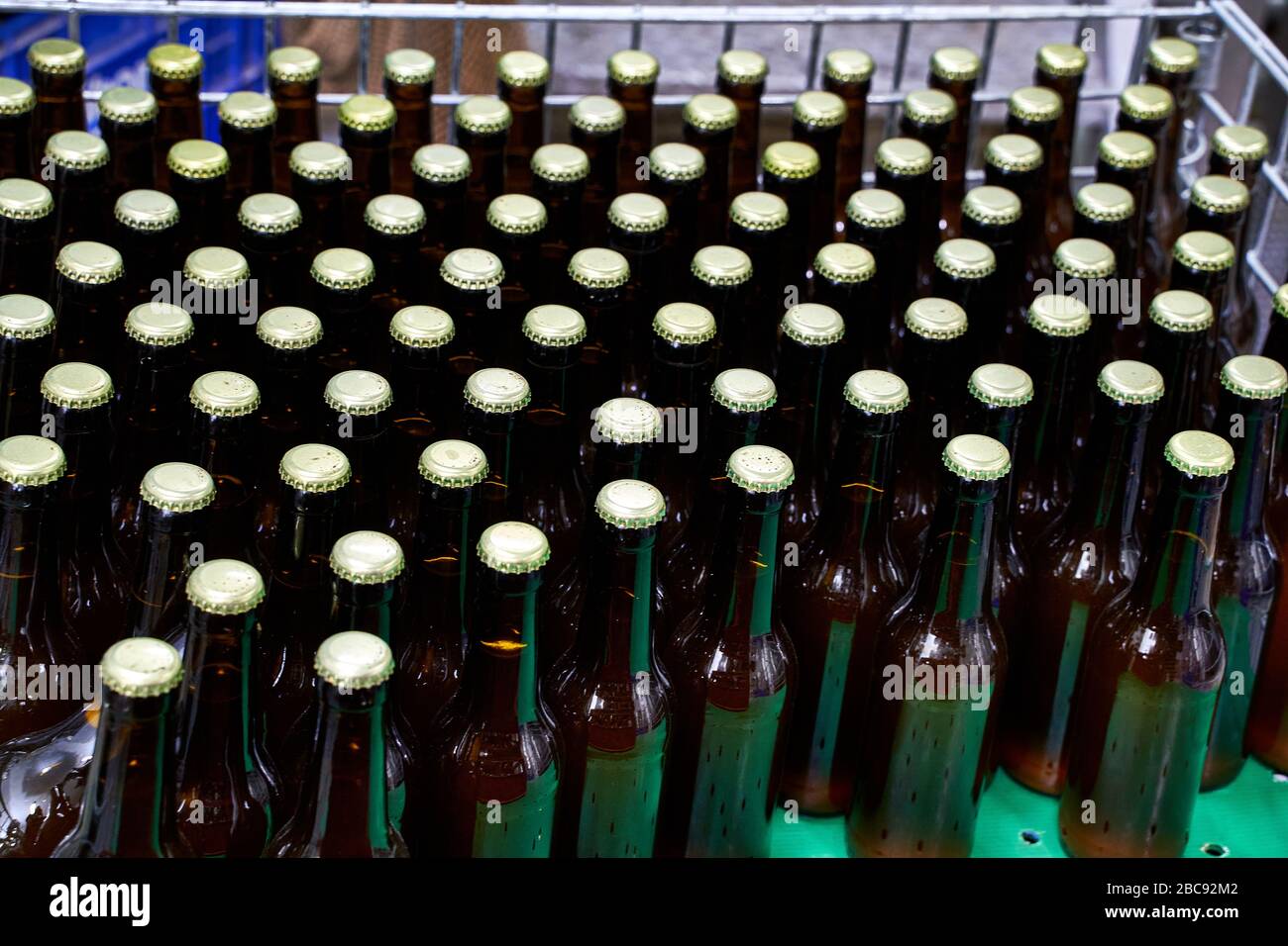 Group of capped beer bottles inside an iron basket in a brewery ...