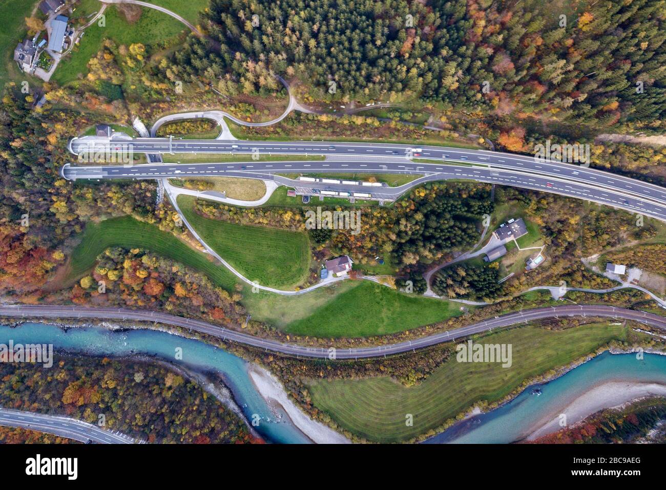 Top dawn aerial view of freeway speed road going out from undeground tunnel between yellow ...