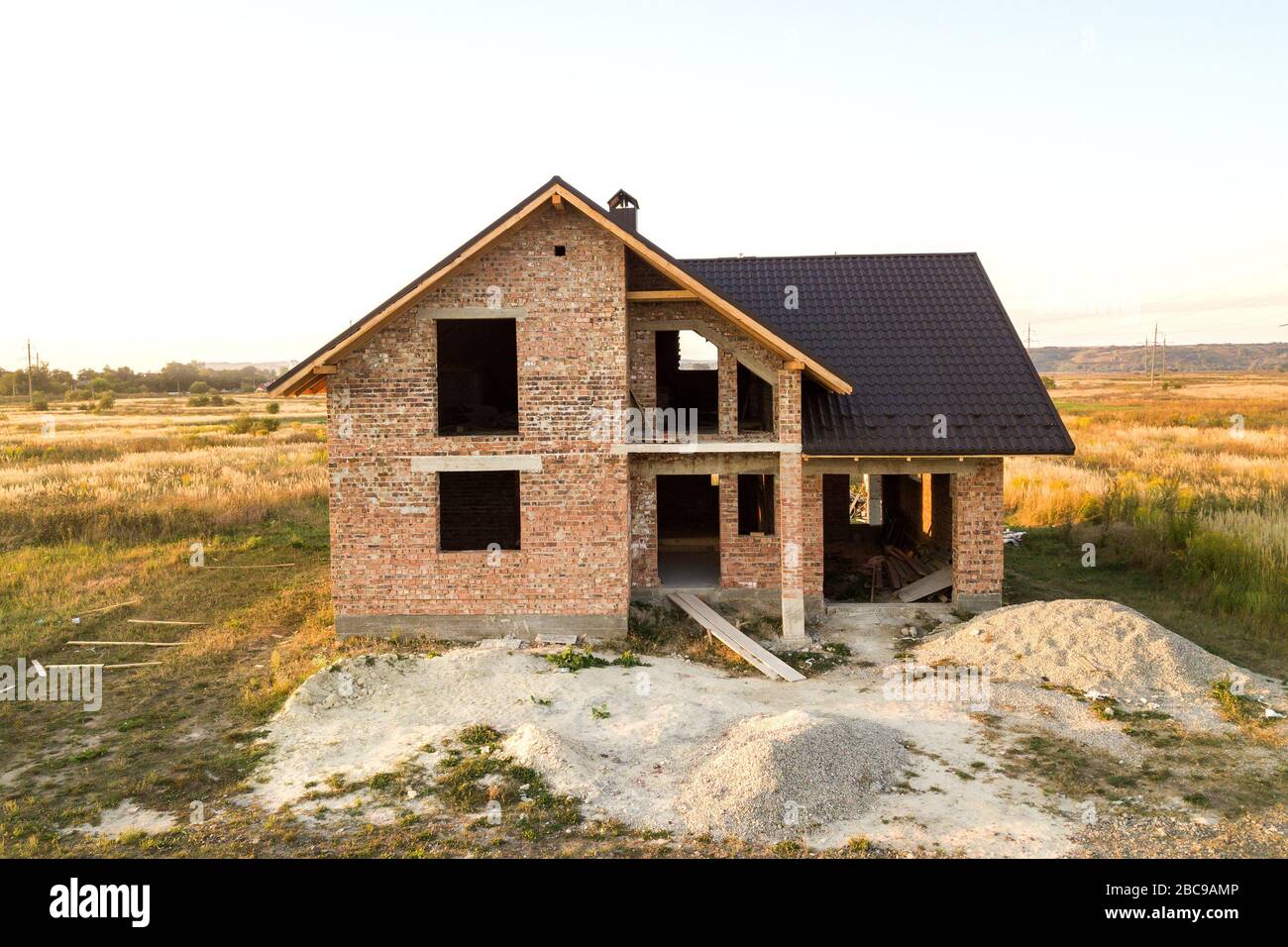 Unfinished brick house with wooden roof structure covered with metal ...