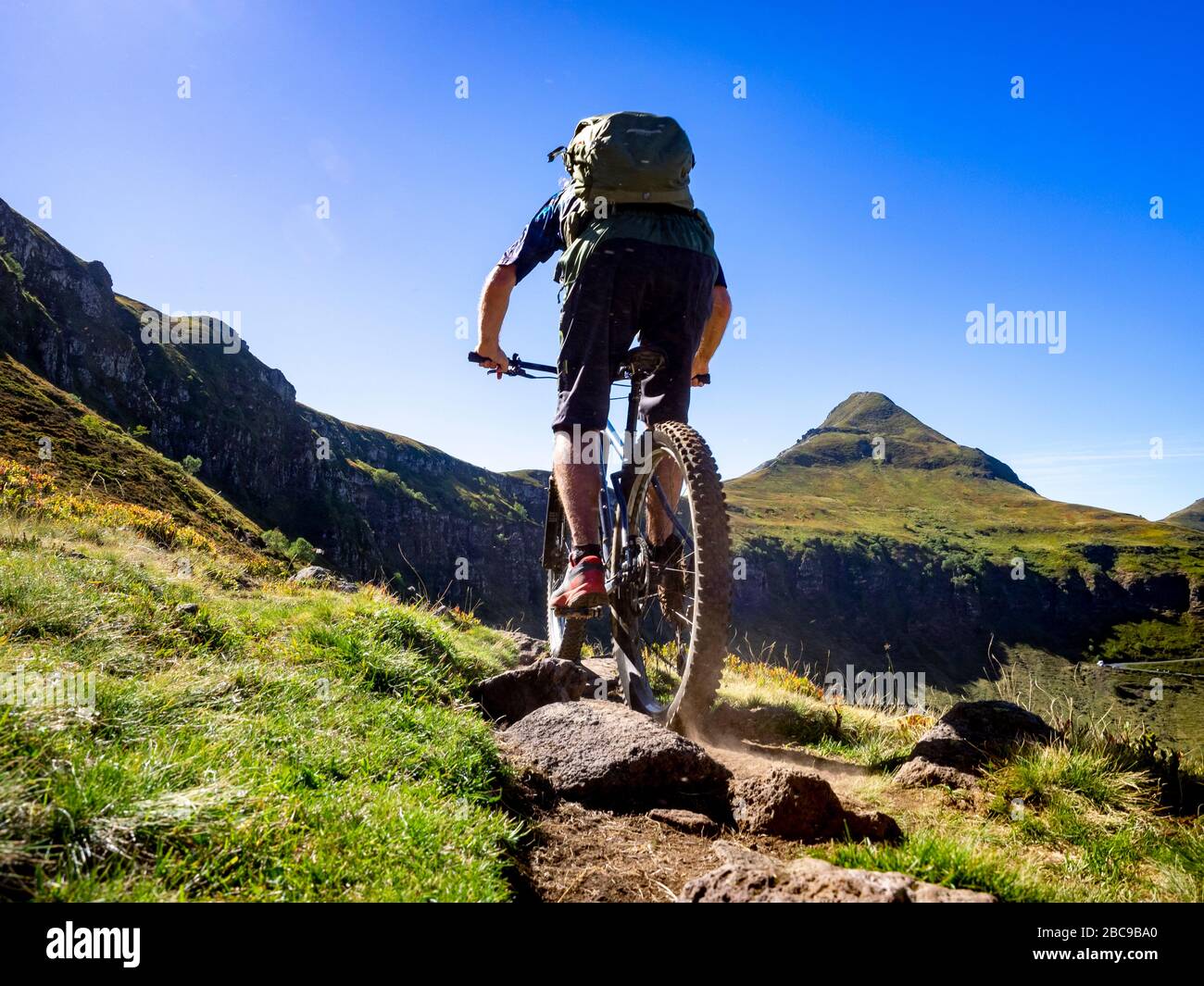 Mountain bikers on a single trail at the Col de Cabre. View of the Puy ...