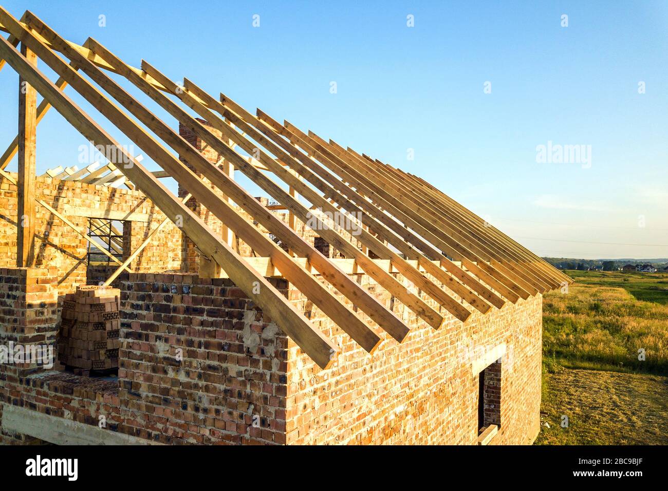 Unfinished brick house with wooden roof structure under construction ...