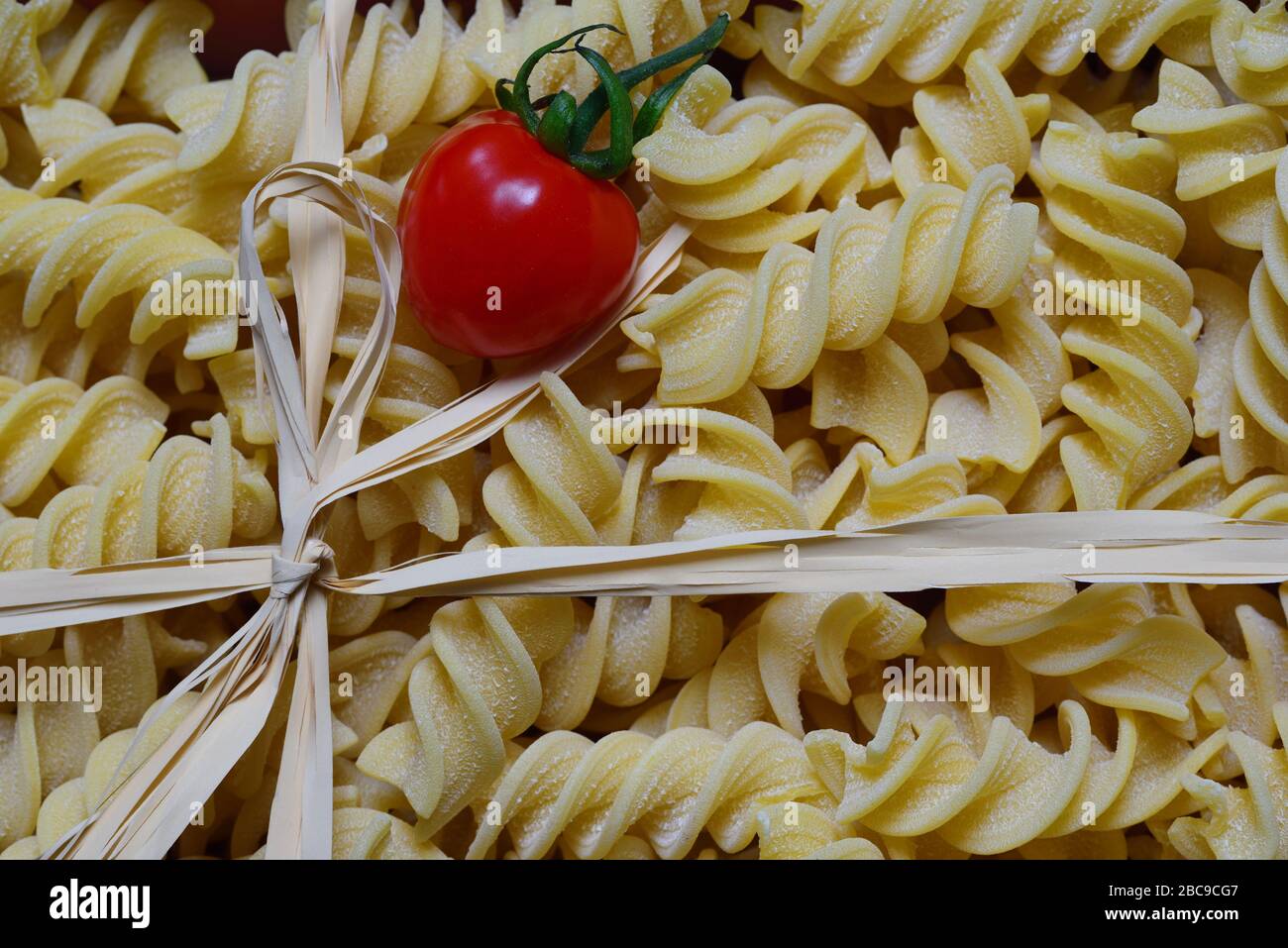 Close-up, background and texture of raw spiral pasta wrapped in a bast ...