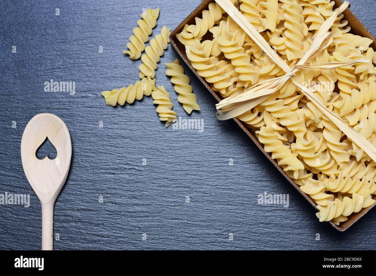 Background and space for text with a cardboard box of raw spiral pasta ...