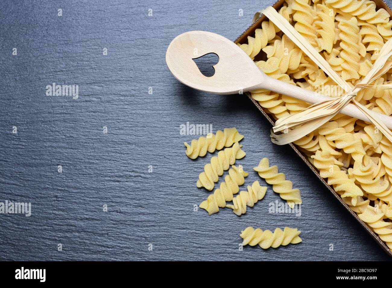 Background and space for text with a cardboard box of raw spiral pasta ...