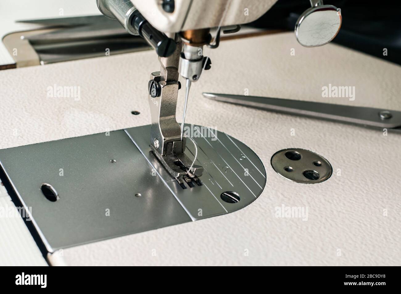 Needle and foot of sewing machine closeup as manufactoring background ...