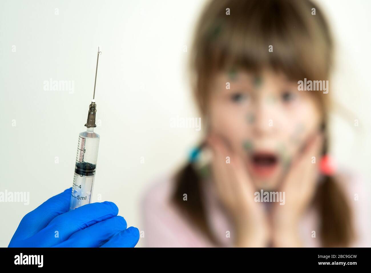 Doctor preparing vaccination injection with a syringe to an afraid ...