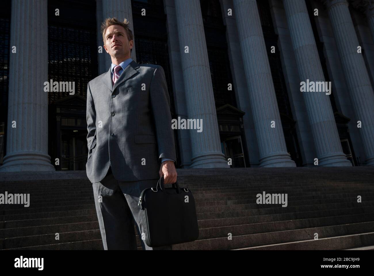 Confident lawyer businessman standing on dark steps with grand ...