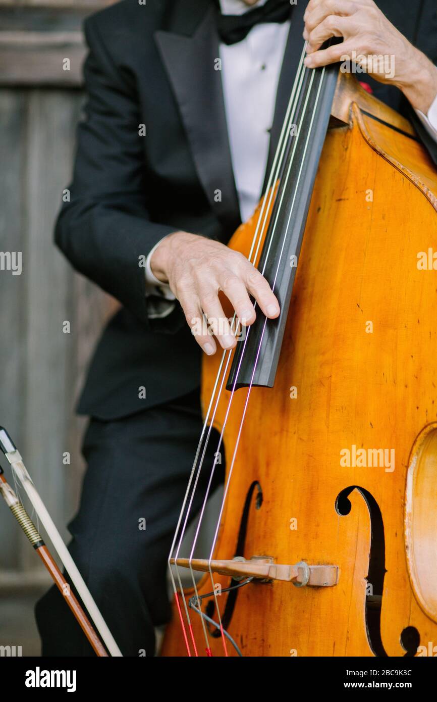 Close up of a cello being played in formal attire Stock Photo - Alamy