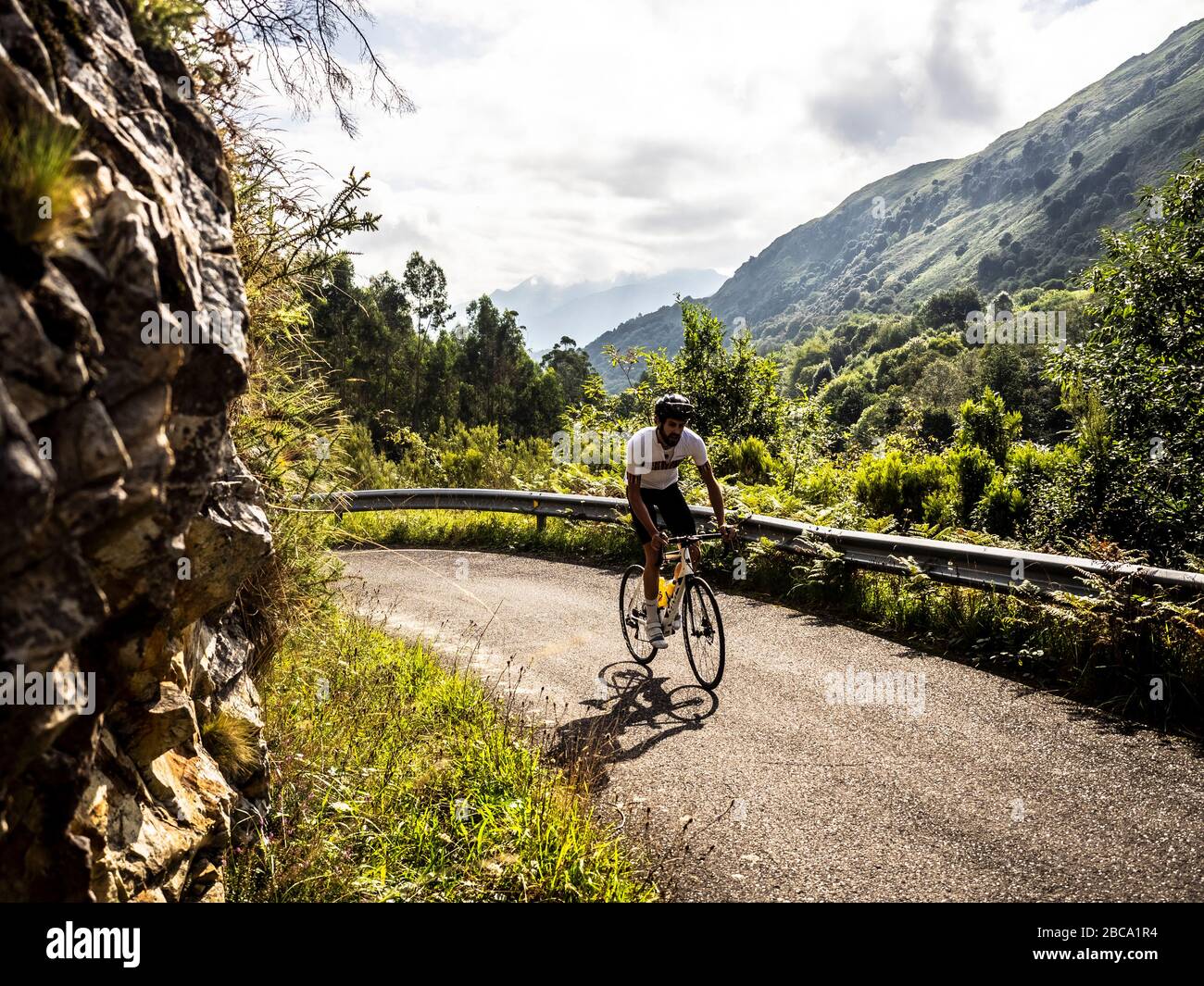 Road cycling in Asturias, northern Spain. Racing cyclist on steep ...