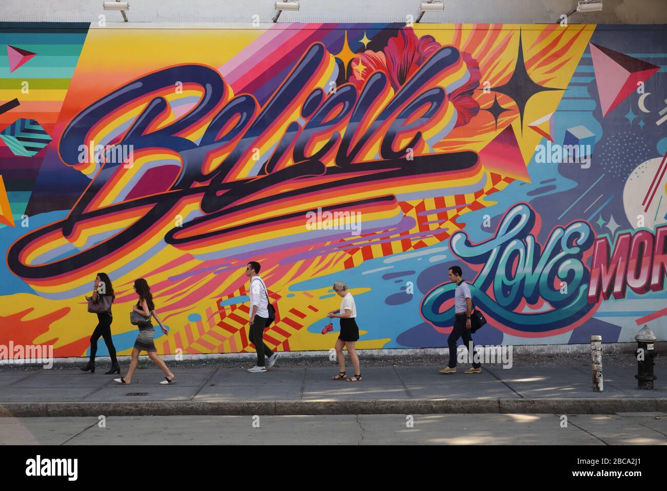 People walking past a mural painted by Queen Andrea entitled Believe on ...