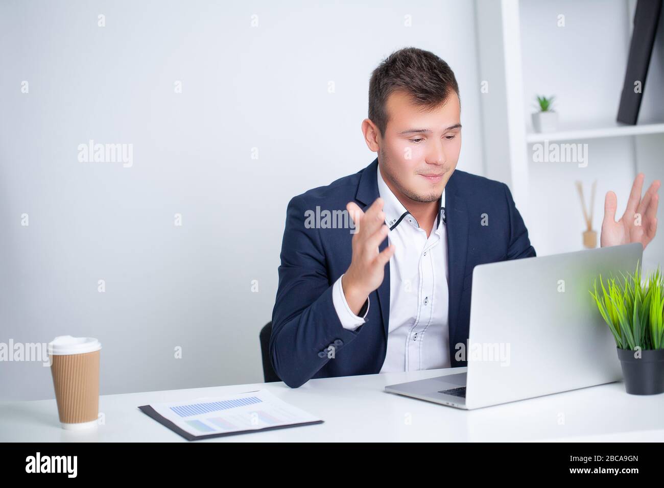 Handsome young worker working in a company office with documents and a ...