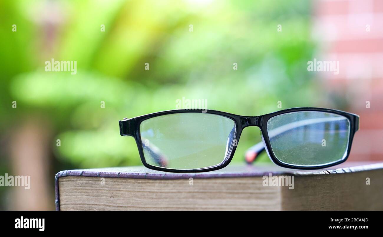 Stack of books with reading glasses on top. Green nature background ...