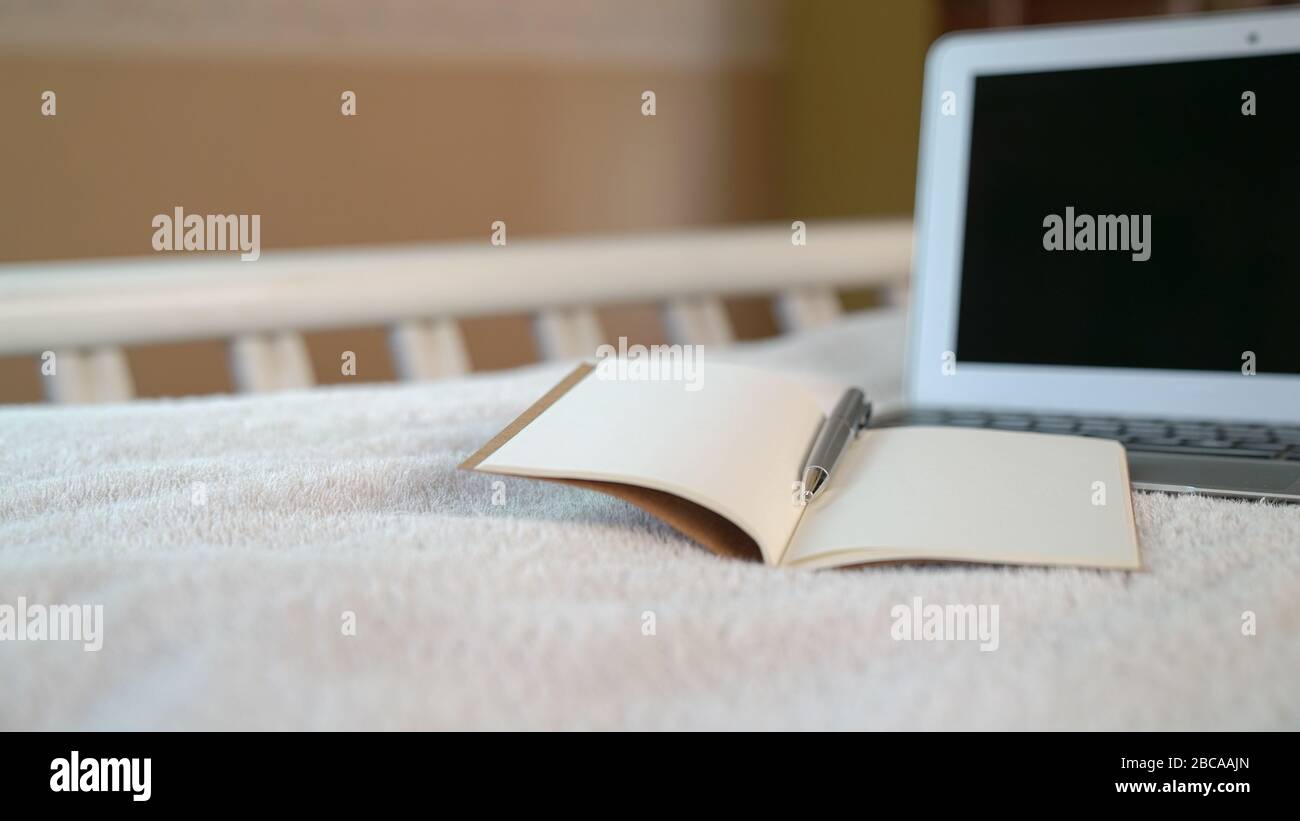 Work space at home with computer laptop and notepad on top of bed. Copy ...