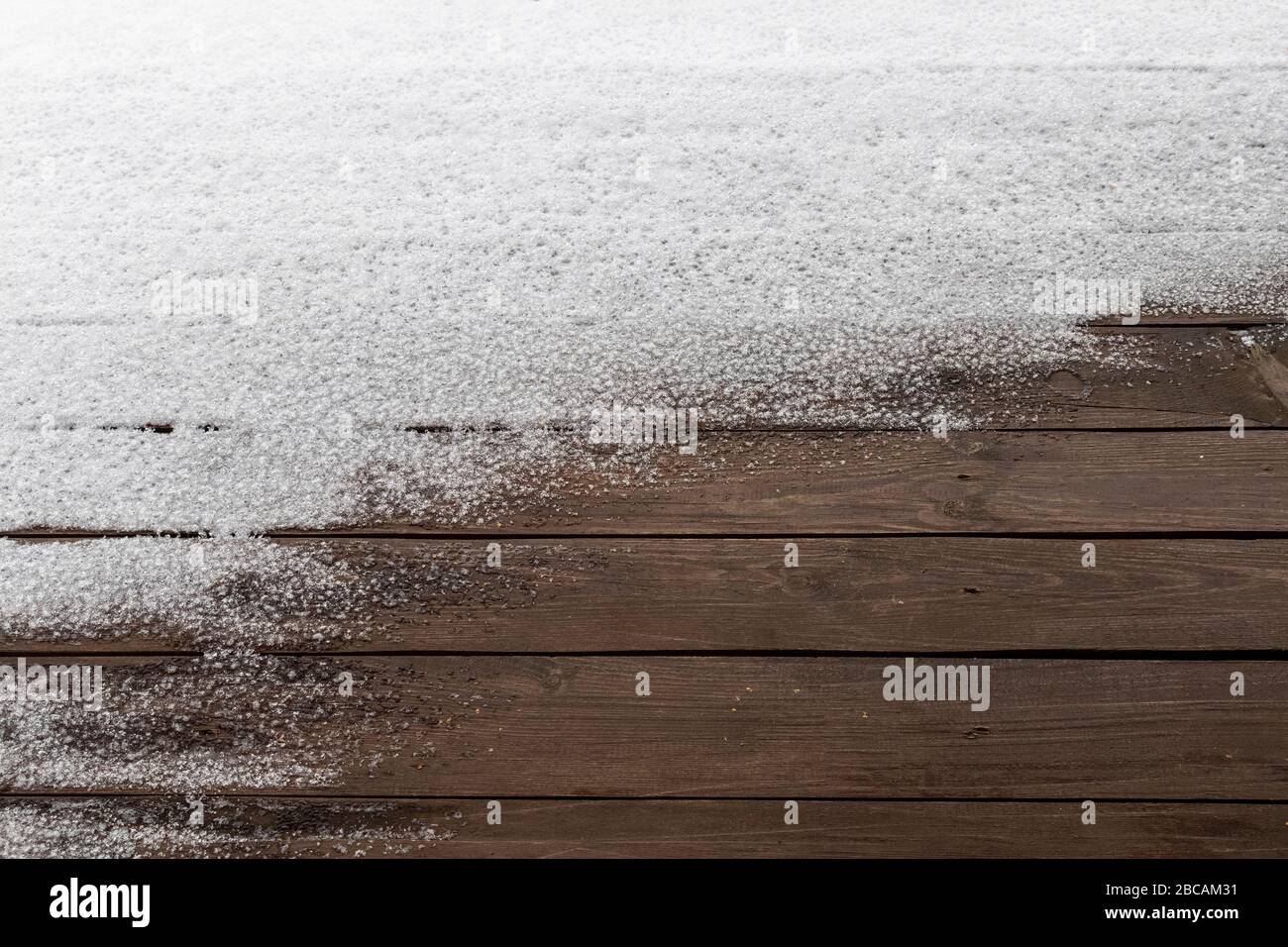 Snow on a wooden plank floor of an open terrace close-up as a ...