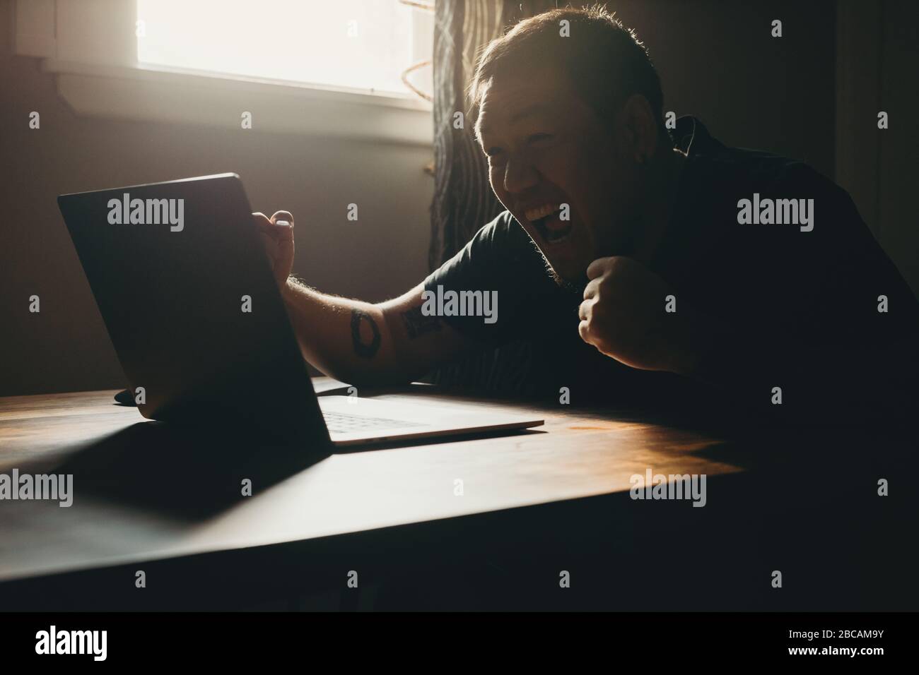 A asian man working on laptop in dark area. Exciting gesture Stock ...
