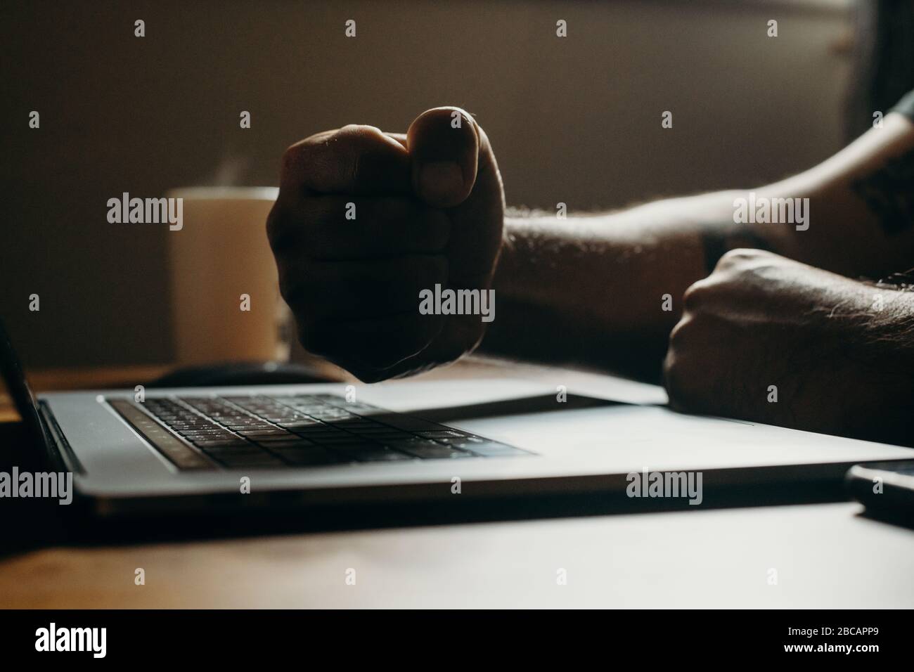Side view closeup shot of man hitting laptop in dark area. Working ...