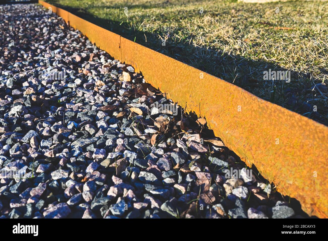 rusty metal edge between grass and gravel Stock Photo - Alamy