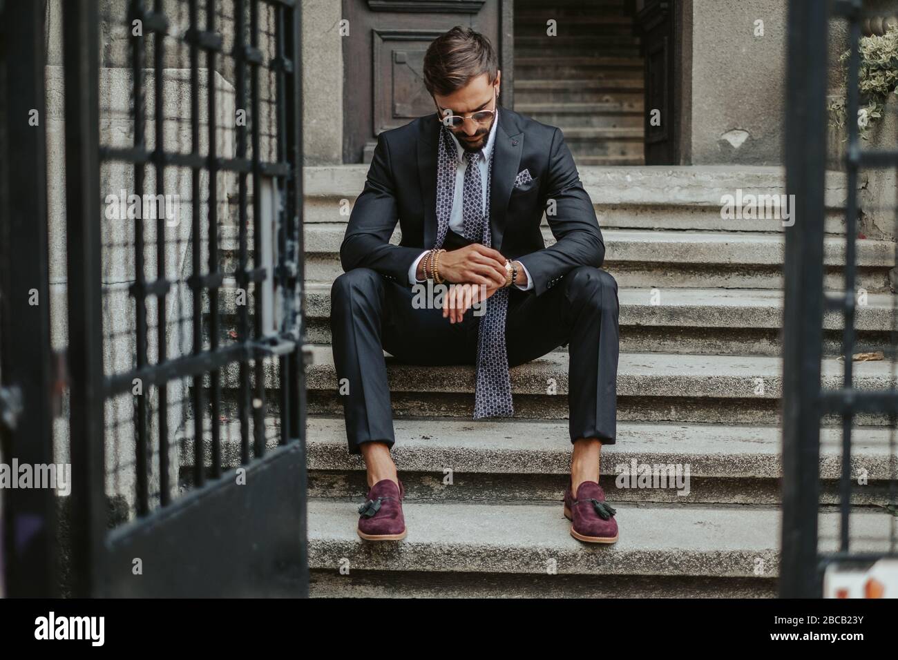 Nervous businessman waiting on the stairs in daytime and looking at the ...