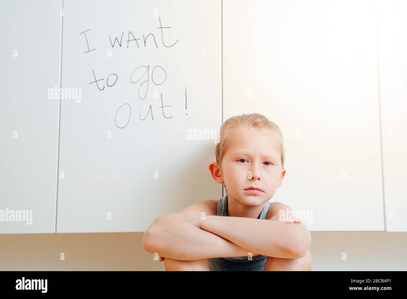 Sad little boy sitting under a board with a message stating his ...