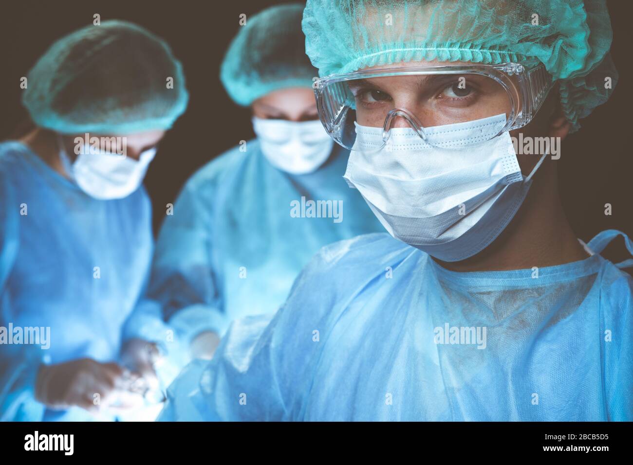 Group of surgeons wearing safety masks performing operation. Medicine ...