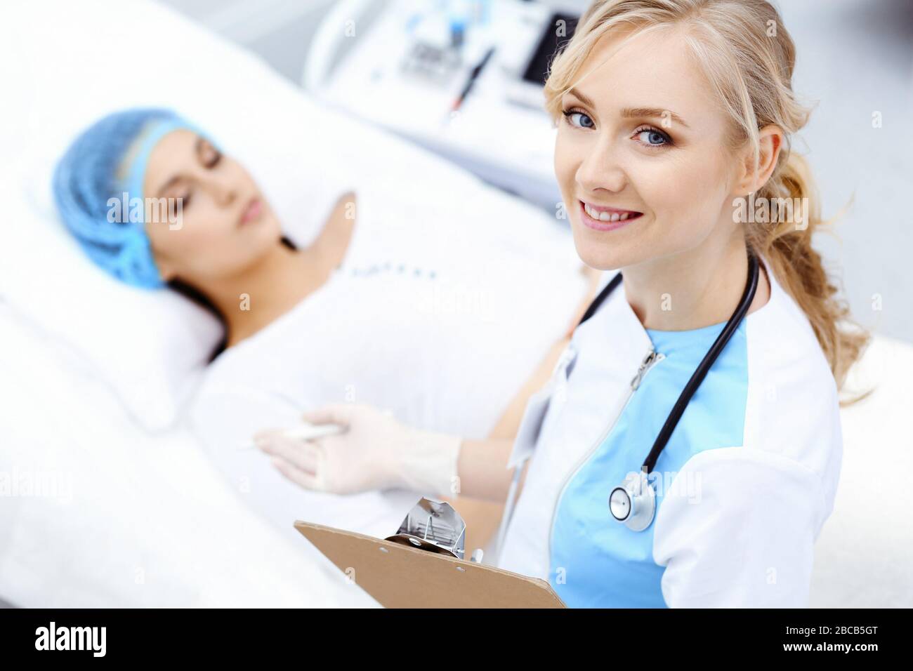 Female doctor and young woman patient in hospital. Physicians examine girl lying at the bed ...