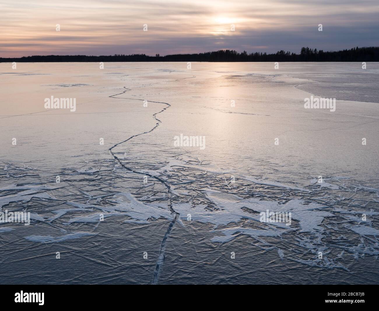 Frozen lake landscape with cracked ice cover Stock Photo - Alamy
