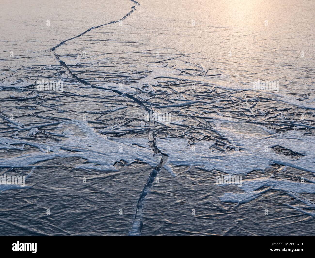 Cracked ice cover at frozen lake Stock Photo - Alamy