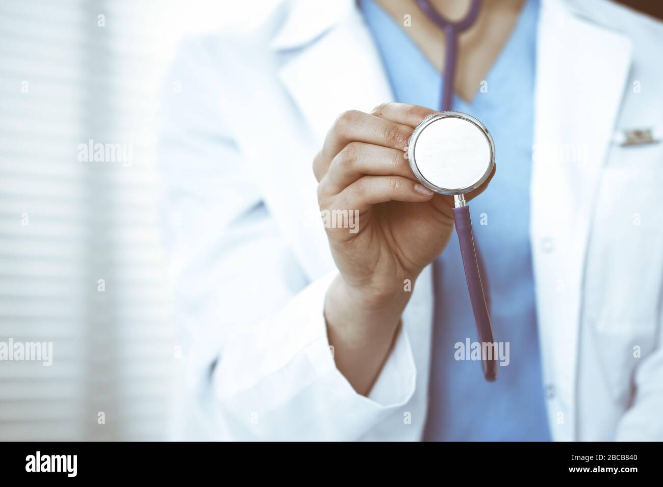 Unknown doctor woman holds stethoscope head, close-up. Physician ready ...