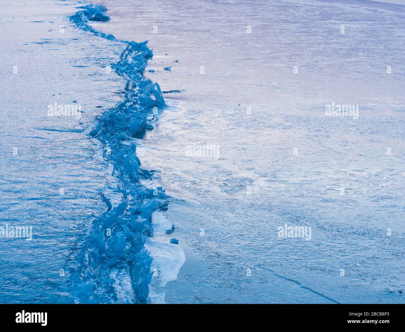 Formation of cracked ice on frozen lake Stock Photo - Alamy