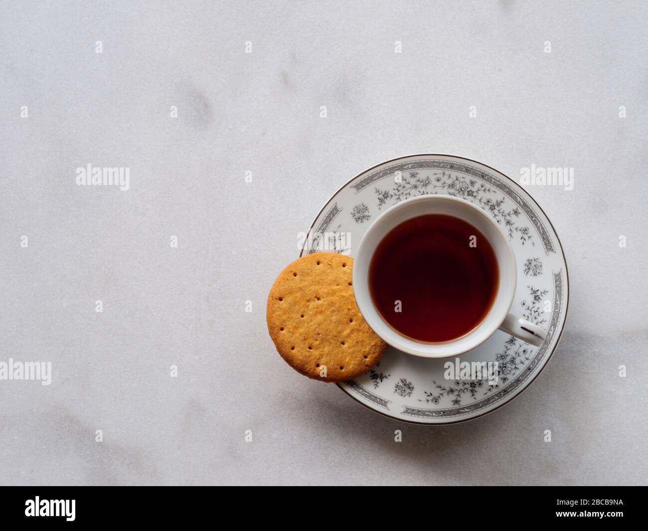 Flat lay of English tea in a fine porcelain china cup with a digestive ...