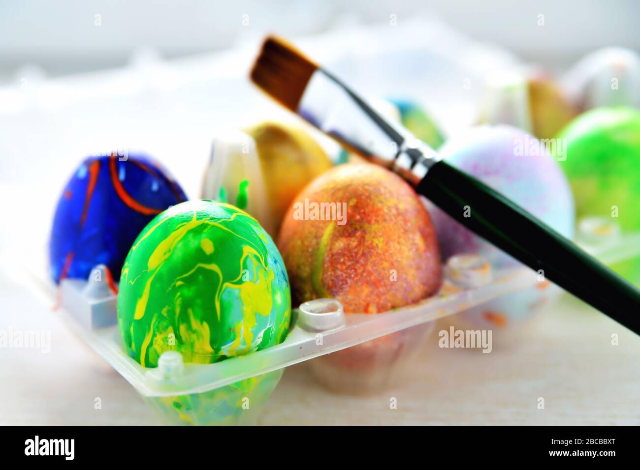 Colored eggs in a transparent box and an art brush, a blurred ...