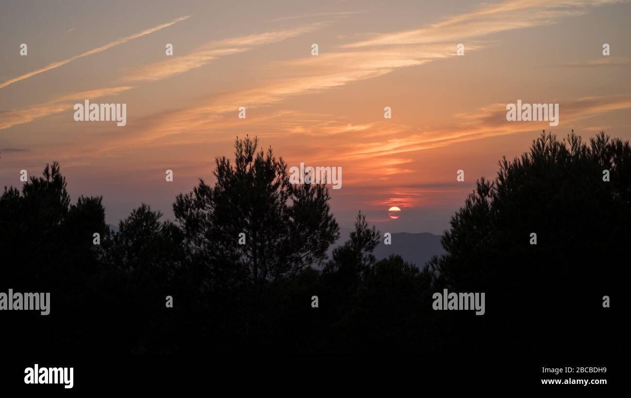 A sun setting into distant low clouds just above the horizon as seen ...