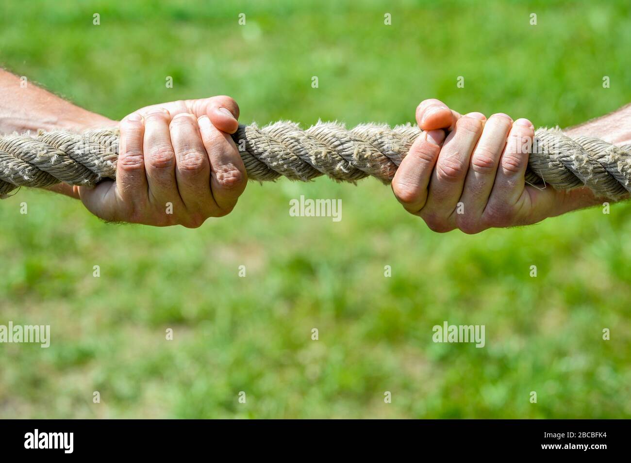 Two men's hands pull the rope each in his own direction. The concept of ...