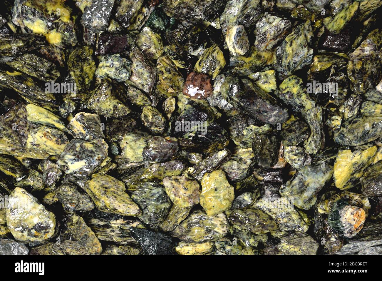 wet small gray-green stones of heterogeneous structure, background ...