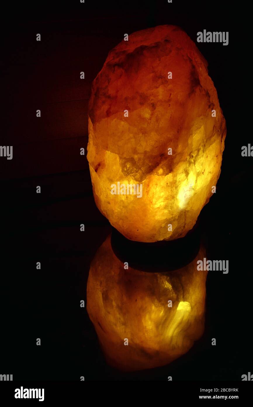 Himalayan rock salt lamp with its own reflection on dark background ...