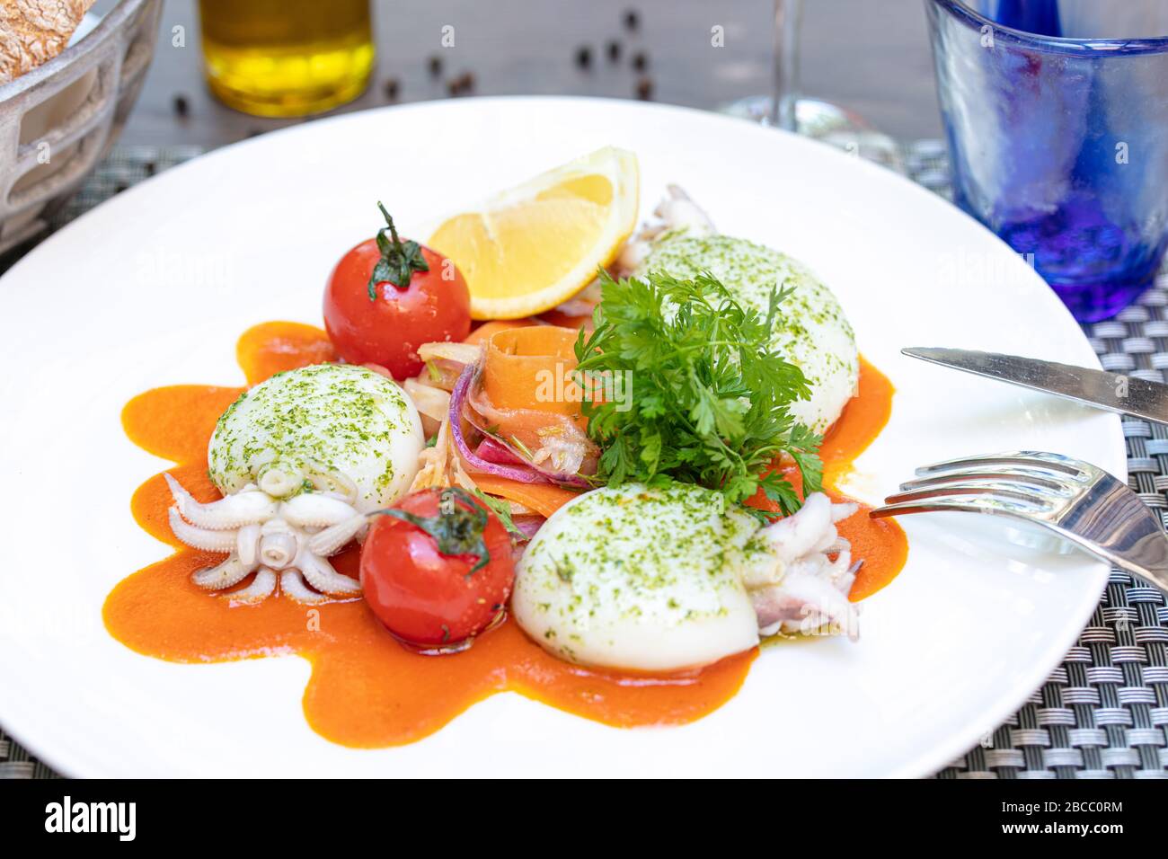 Plate of cuttlefish with tomatoes in a restaurant Stock Photo - Alamy
