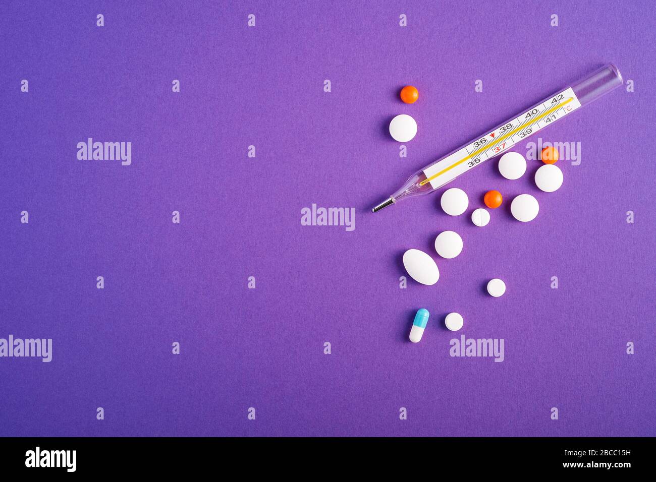Pills, tablets and analog thermometer on violet purple background ...