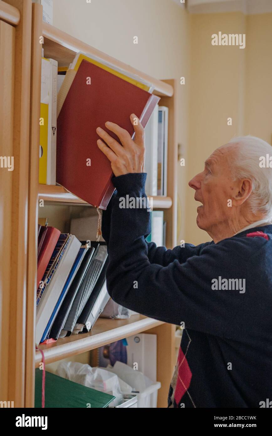 Old man reading book sitting on couch Stock Photo - Alamy