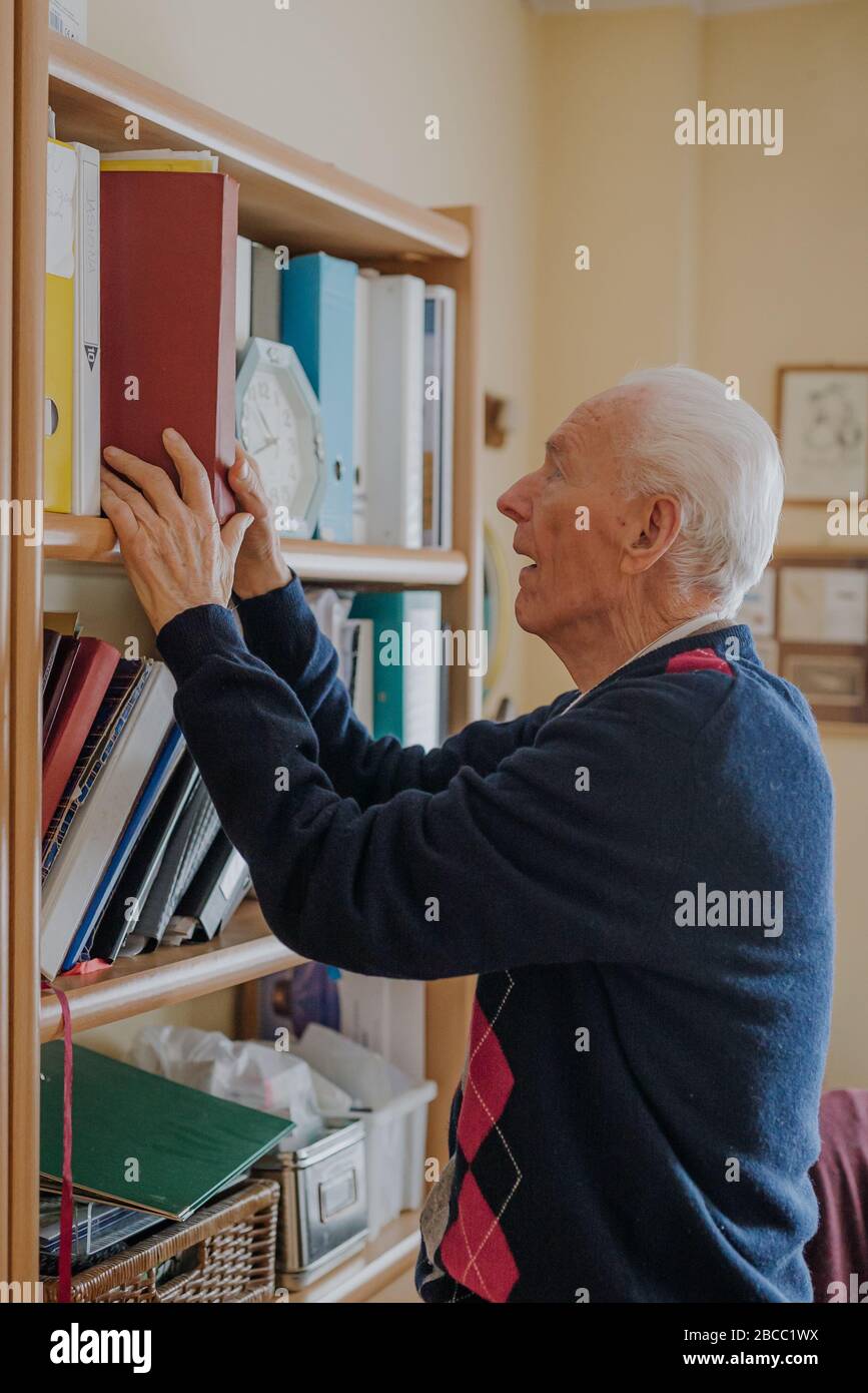Old man reading book sitting on couch Stock Photo - Alamy
